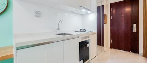 Uma cozinha moderna com armários brancos, pia de aço inoxidável e lava-louças embutida.