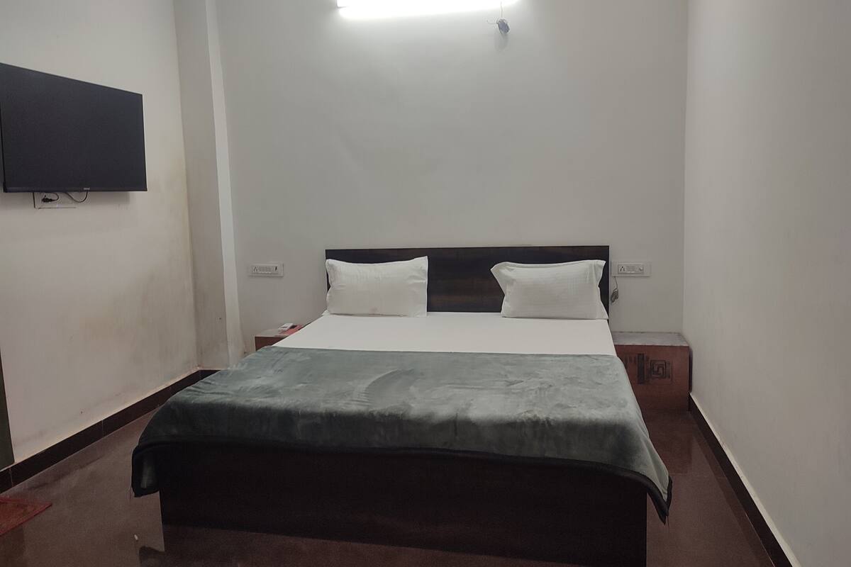 Quarto de hotel com cama, televisão de tela plana na parede e mesa de cabeceira.