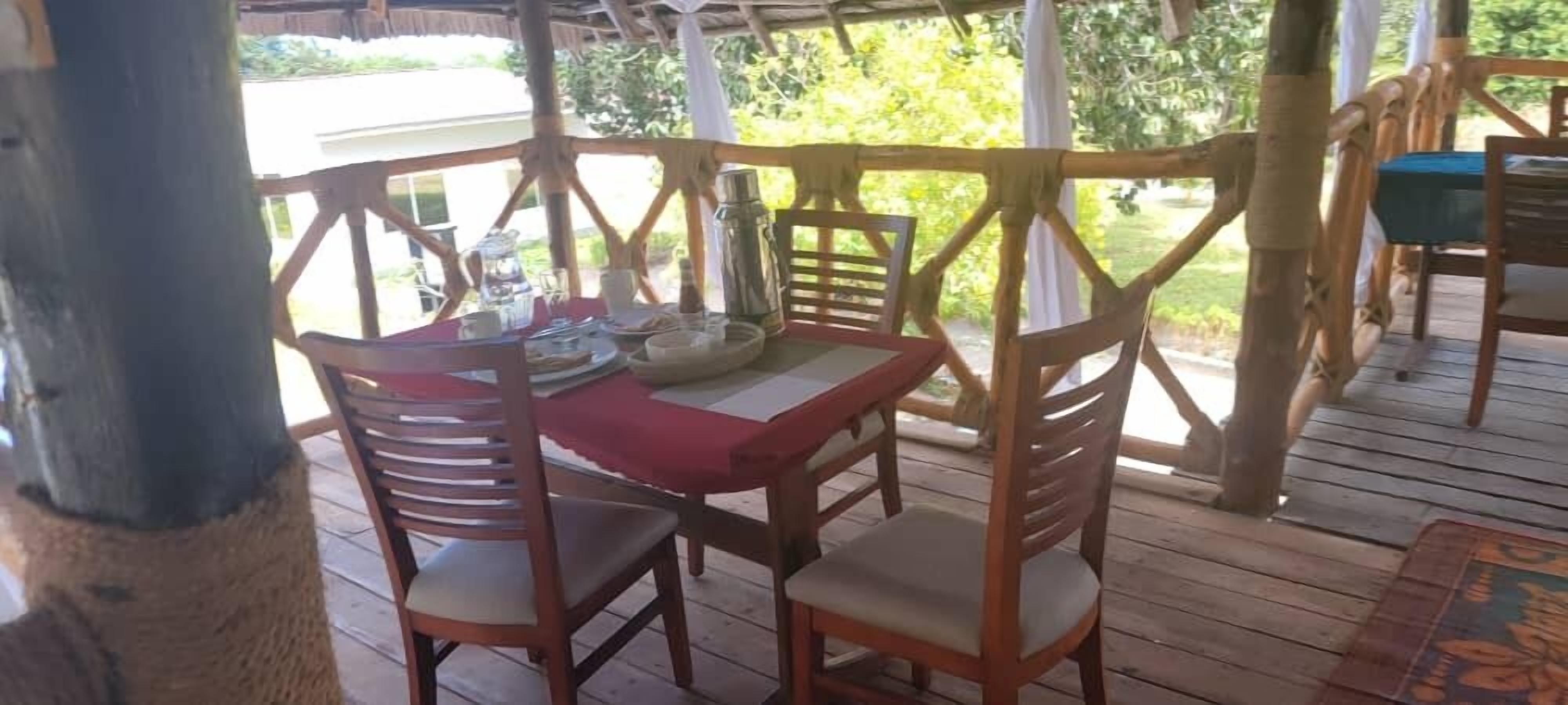 Um deck de madeira com mesa e cadeiras, uma garrafa de água de metal e um jarro de vidro.