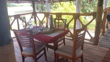 Um deck de madeira com mesa e cadeiras, uma garrafa de água de metal e um jarro de vidro.