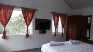 Quarto com cama, cortinas, televisão e guarda-roupa.