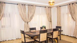 Uma área de jantar com uma mesa redonda, seis cadeiras e um vaso com flores.
