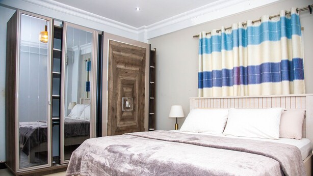 Quarto com cama, guarda-roupa e zona de duche.