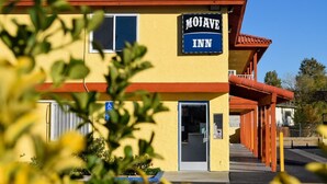 Um edifício amarelo com telhado vermelho, com a placa 'MOJAVE INN'.