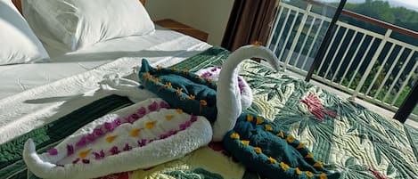 Uma cama com colcha verde e toalha decorativa em formato de cisne.