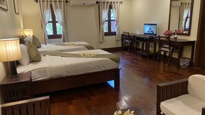 Quarto de hotel com duas camas, uma escrivaninha, uma cadeira, uma televisão e uma mesa de jantar.
