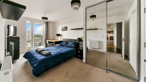Quarto moderno com uma cama grande, uma escrivaninha e uma porta de armário deslizante.