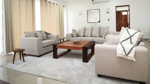 Uma sala de estar com um sofá, uma mesa de centro e uma pequena mesa lateral.
