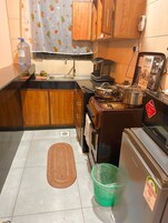Cozinha compacta com armários de madeira, fogão, geladeira e micro-ondas.