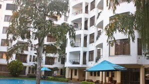 Um hotel com vários andares, varandas, piscina e área de estar ao ar livre.