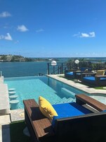 Uma área de piscina com espreguiçadeiras e vista para o oceano.