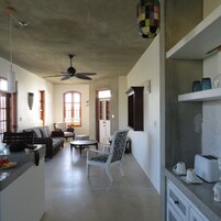 Uma sala de estar ampla, com ventilador de teto, mesa de jantar e espaço de cozinha com torradeira.