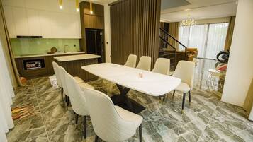 Cozinha moderna com área de jantar, piso de mármore, mobiliário contemporâneo e escada que leva a um andar superior.