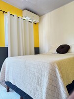 Uma cama com colcha acolchoada, travesseiro preto e cabeceira branca.