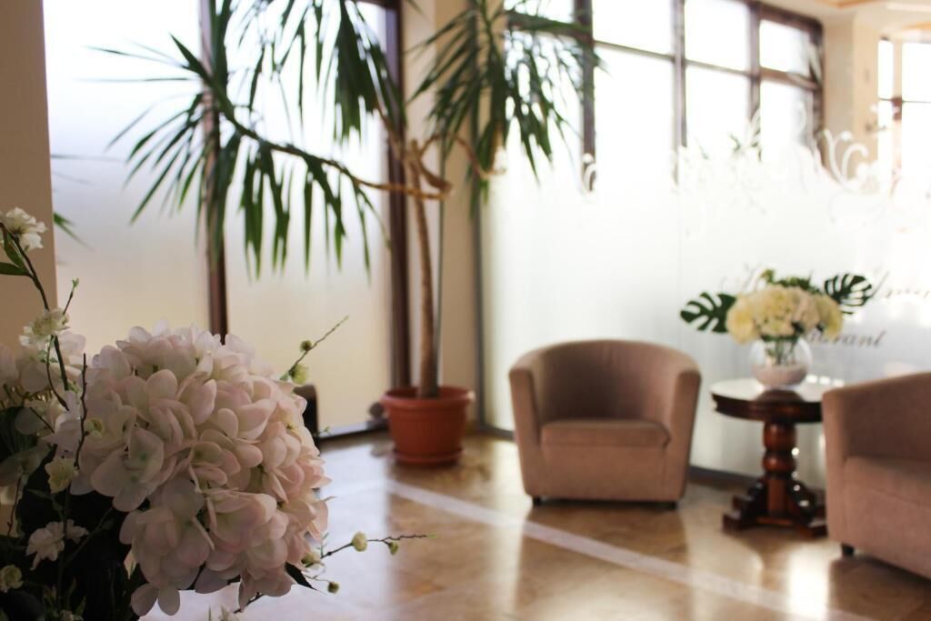 Quarto com uma janela grande, uma planta em vaso, uma cadeira e uma mesa com um vaso de flores.