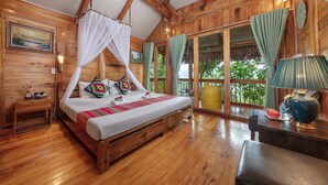 Um quarto de madeira com uma cama, uma mesinha de cabeceira, uma luminária e uma janela grande.