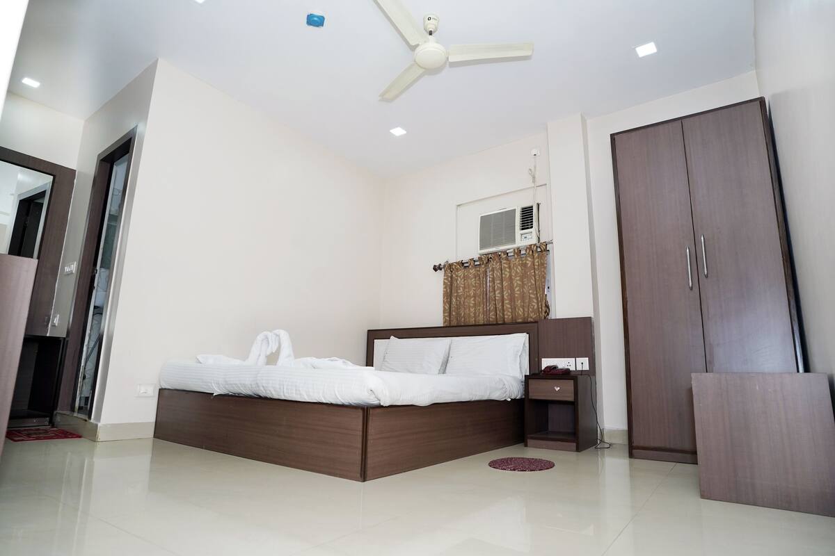 Um quarto moderno com cama, guarda-roupa, mesa de cabeceira e ventoinha no teto.