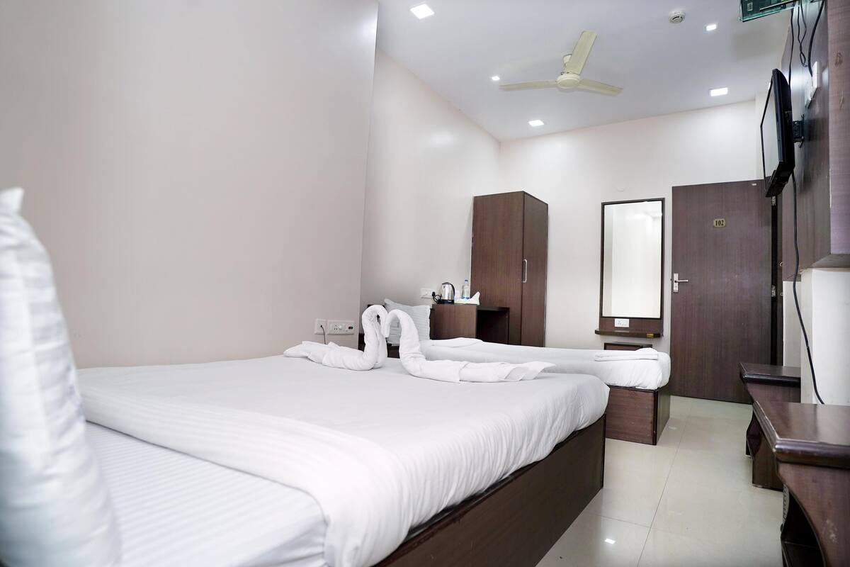 Quarto de hotel com cama, guarda-roupa, secretária, espelho e televisão.