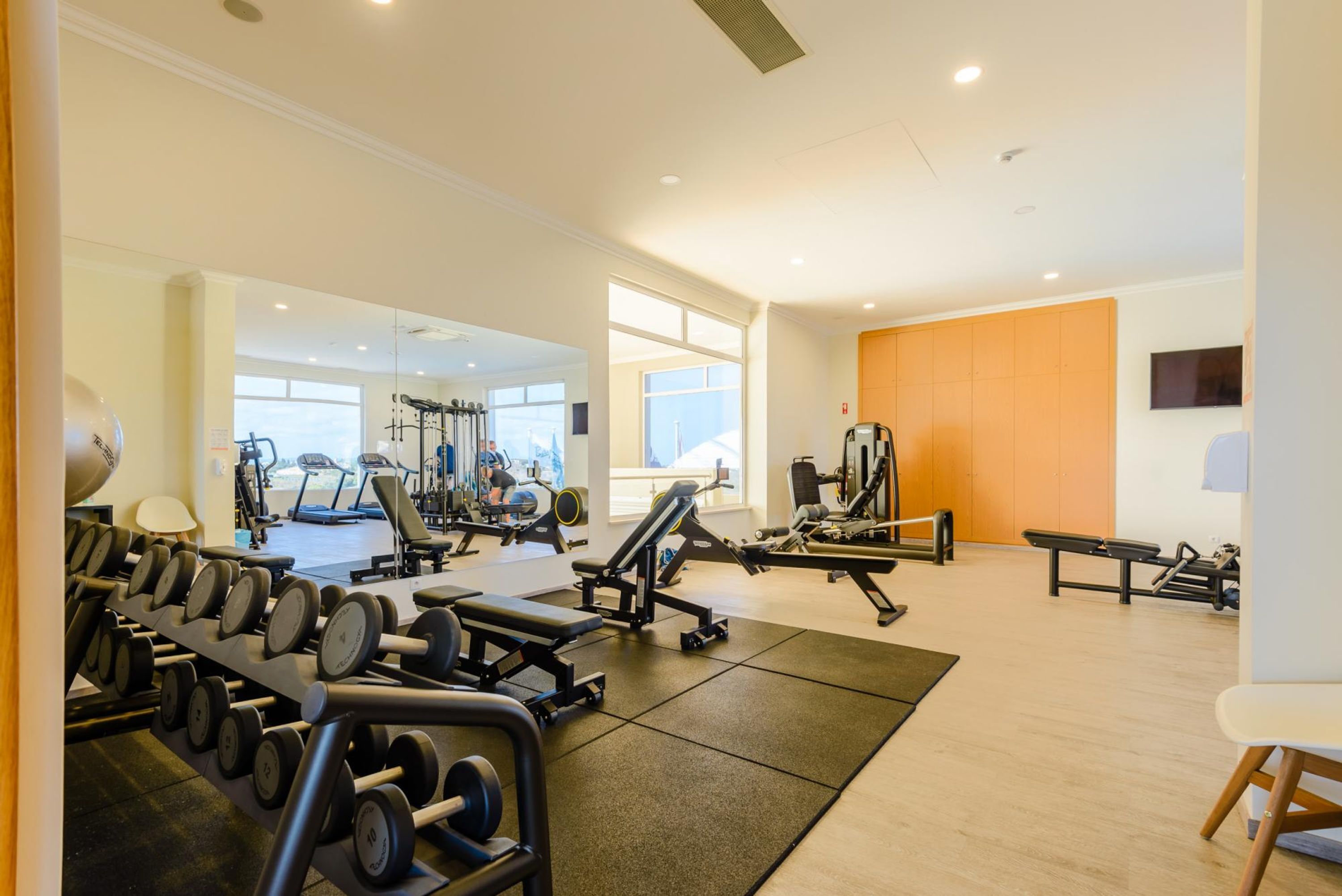 Uma academia com diversos equipamentos de exercícios, incluindo halteres, esteiras e aparelhos de musculação.