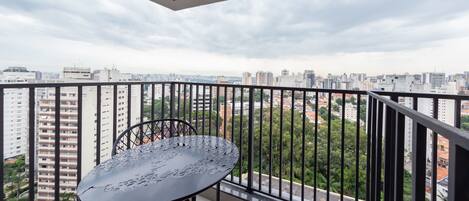 Varanda com mesa e cadeiras, com vista para a cidade.
