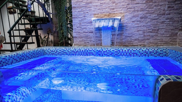 Piscina com cascata e piso de azulejos decorativos.