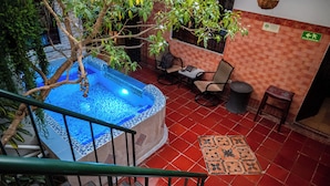 Uma área de hidromassagem com piso de azulejos, uma escadaria e um espaço de estar com cadeiras e uma mesa pequena.