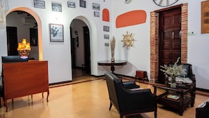 Um hall de entrada com balcão de recepção, relógio, quadros emoldurados e porta com fachada de tijolos.