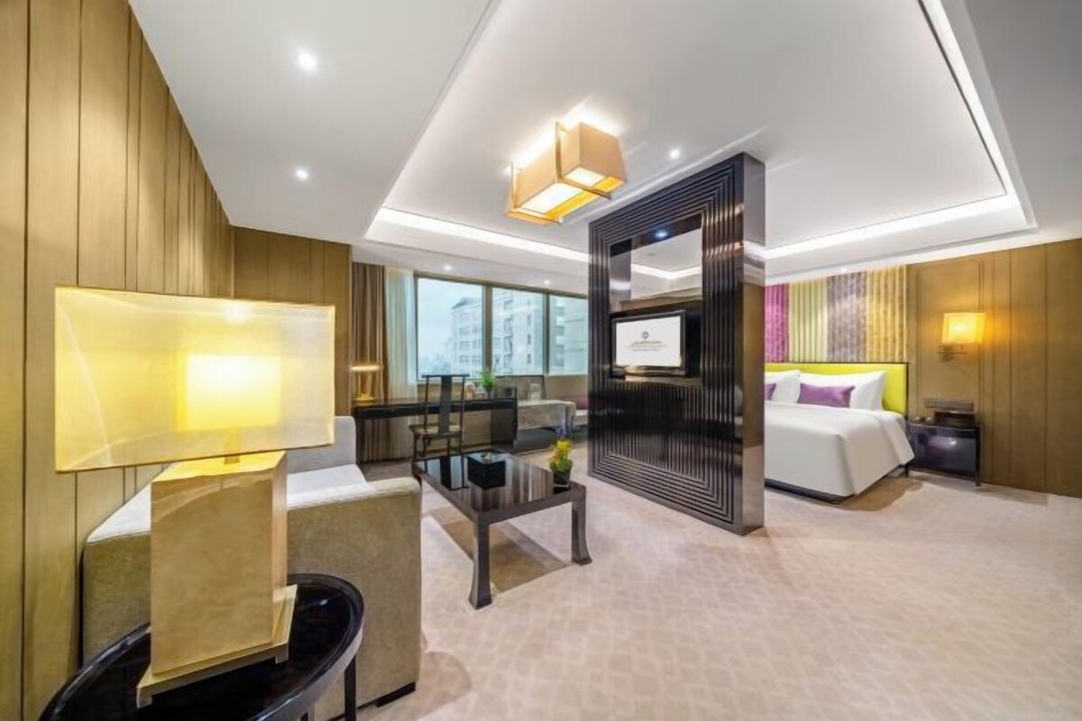 Quarto de hotel moderno com uma cama grande, uma escrivaninha e uma televisão.