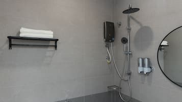 Um banheiro moderno com azulejos cinza, um porta-toalhas preto, um chuveiro manual, um aquecedor de parede e um espelho redondo.
