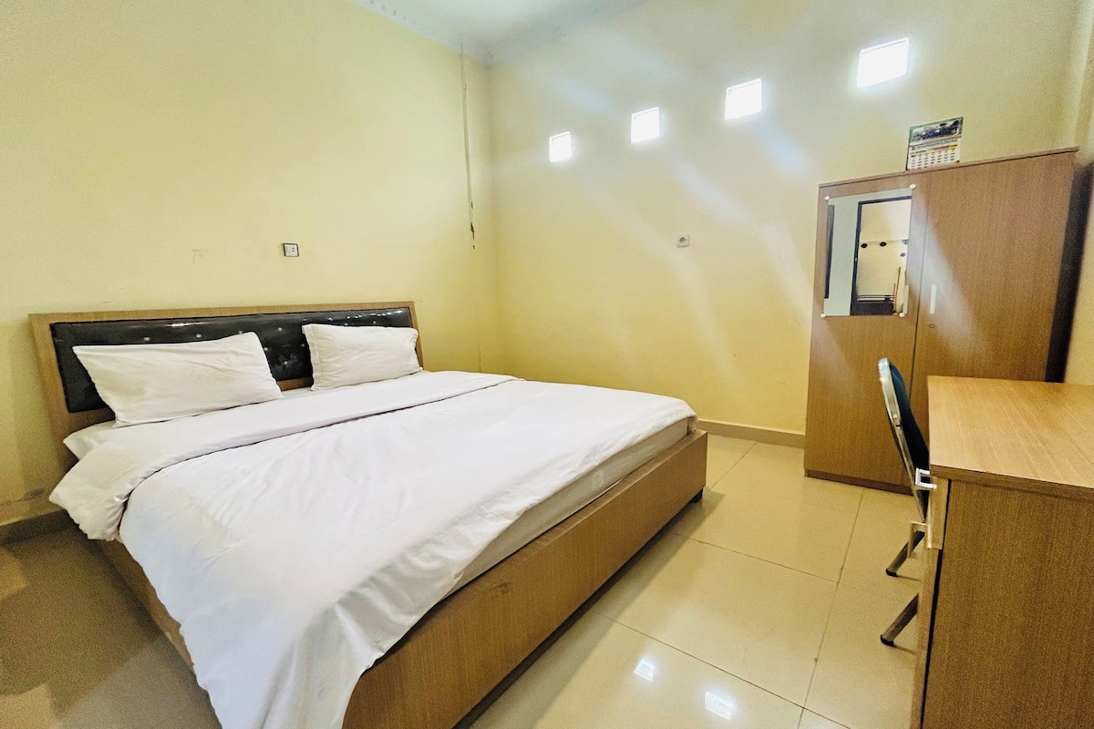 Um quarto com uma cama, uma escrivaninha e um guarda-roupa.