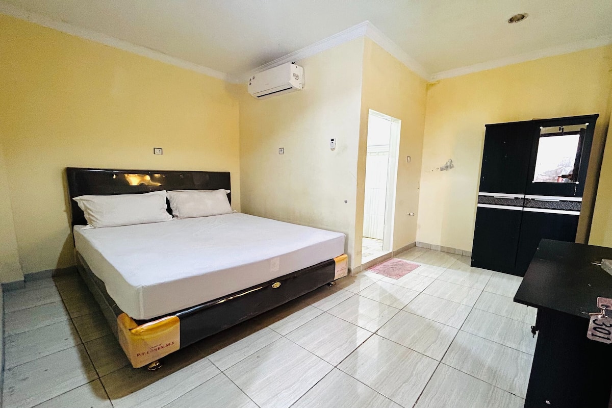 Quarto com cama, escrivaninha, ar-condicionado e guarda-roupa.