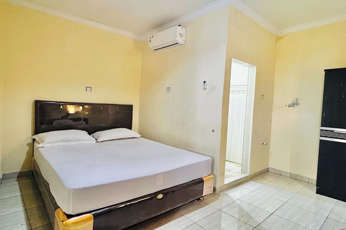 Quarto com uma cama, ar condicionado, uma porta e um armário preto.
