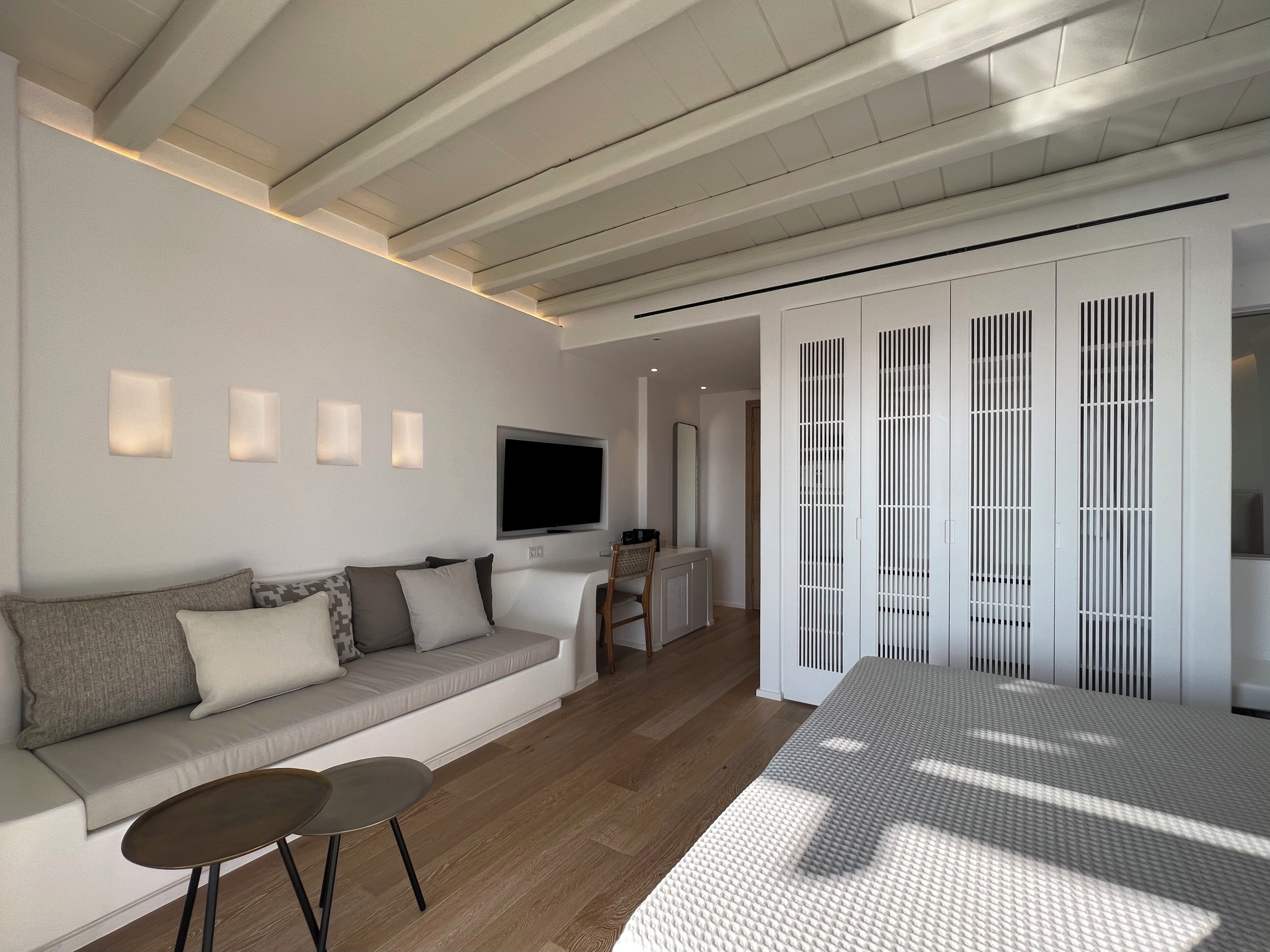 Quarto de hotel moderno com sofá, TV e cama.