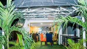 Espaço interior com área coberta, assentos e um bar com garrafas.