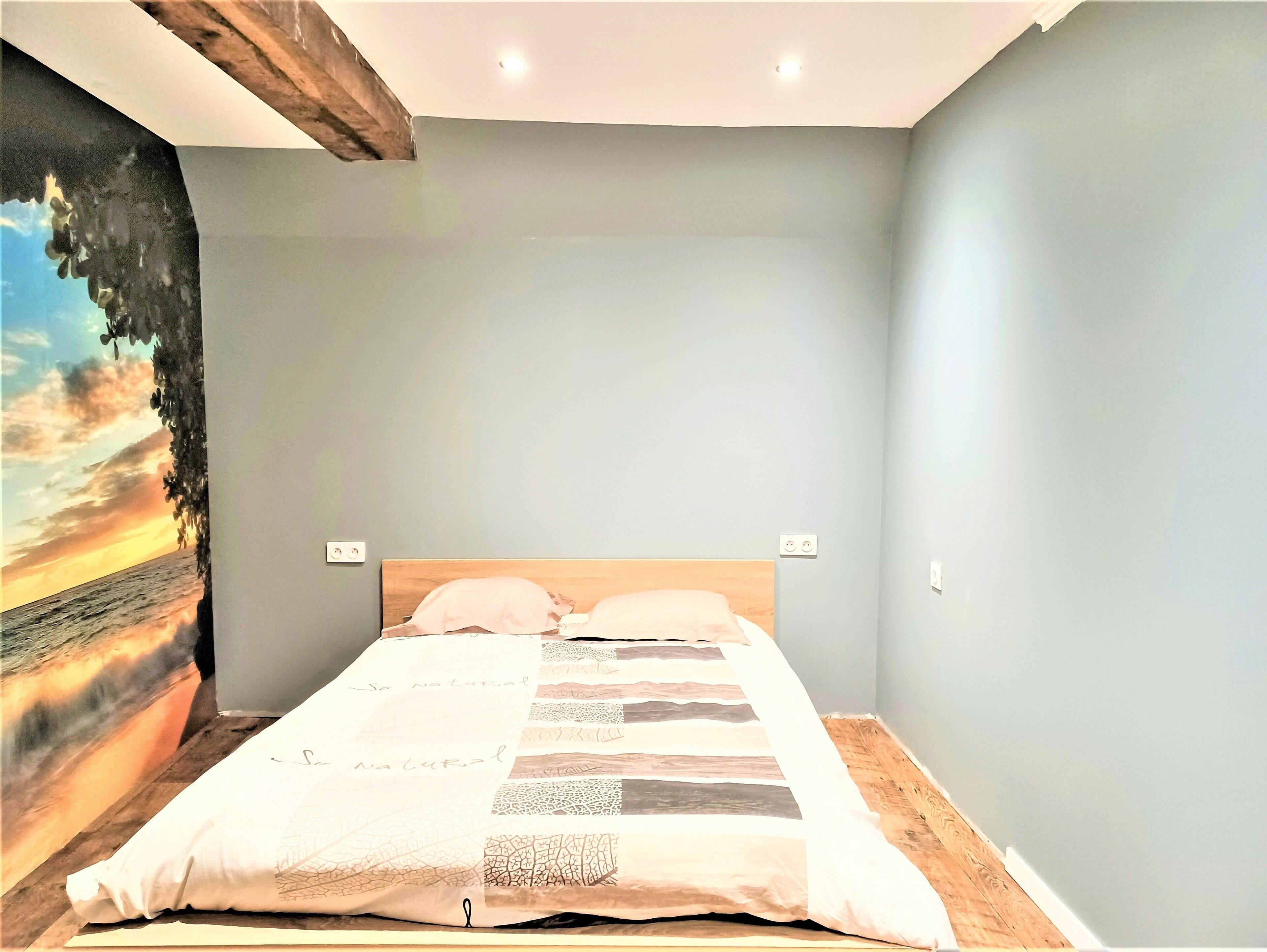Quarto com cama, um mural e uma viga de madeira no teto.