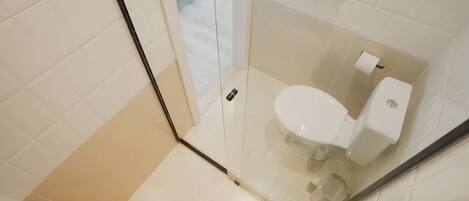 Um banheiro moderno com box de vidro, vaso sanitário branco e porta-toalhas visível.
