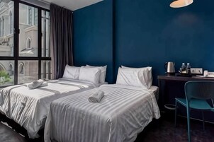Quarto de hotel com duas camas, uma escrivaninha e uma cadeira.