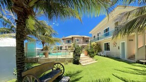 Pátio bem cuidado com piscina, palmeiras e um banco de madeira.
