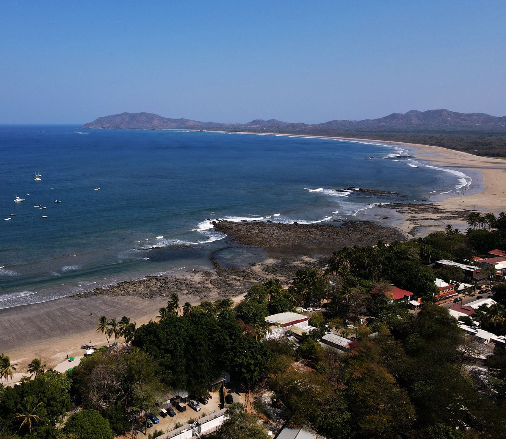 Uma vila costeira com praia, falésias e edifícios residenciais.
