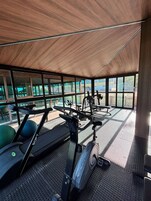 Uma academia com equipamentos de ginástica, janelas amplas e área coberta.