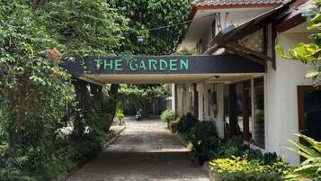 Uma trilha conduz a um edifício com uma placa que diz 'THE GARDEN'.