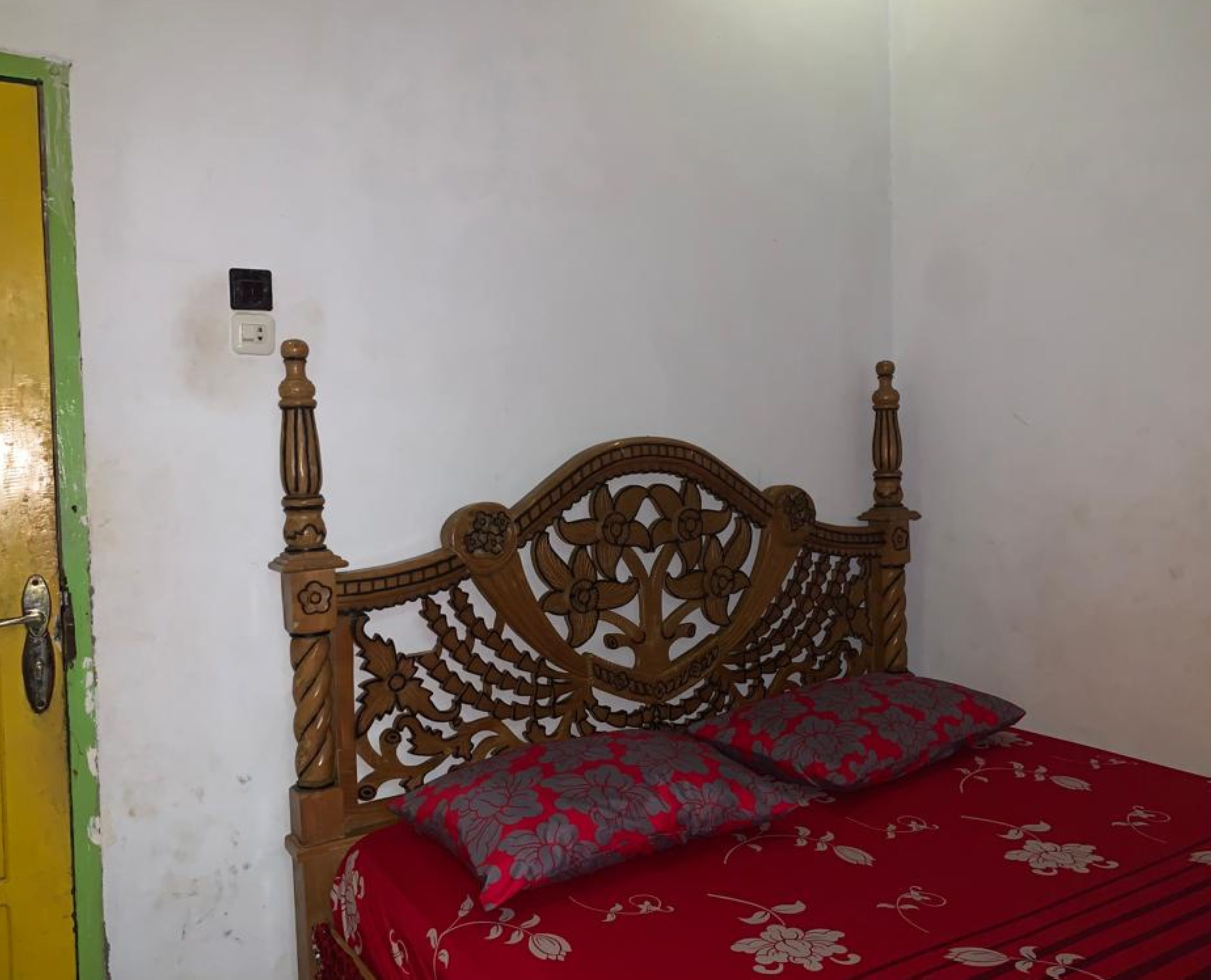 Cama com cabeceira de madeira e roupa de cama com padrão floral.