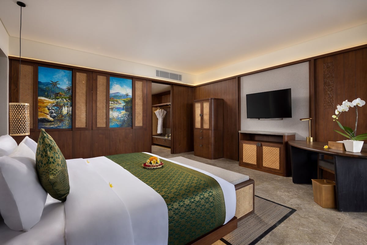 Quarto de hotel com uma cama, televisão, escrivaninha e armário.