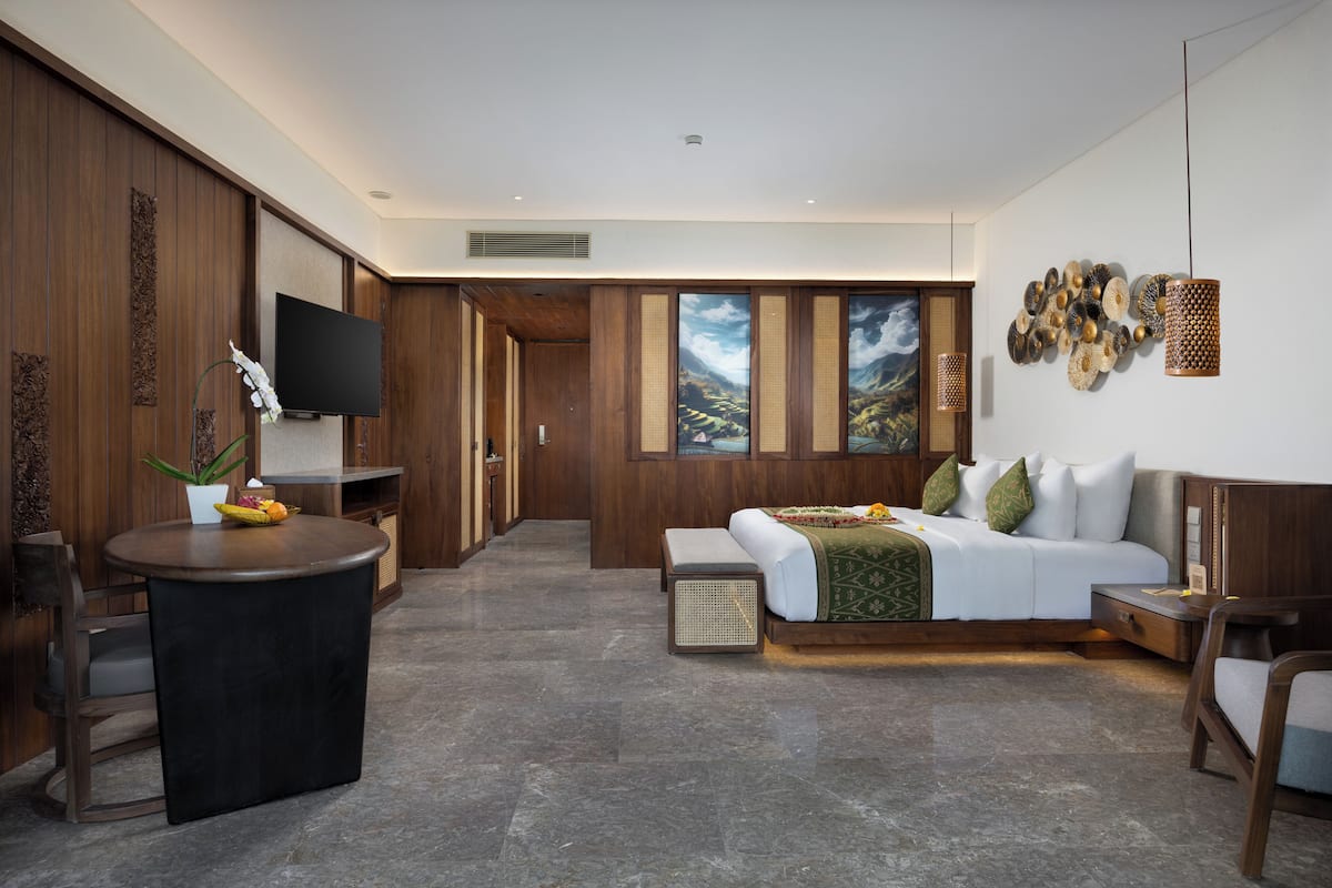 Quarto de hotel moderno com cama, escrivaninha, televisão e uma grande janela com vista para as montanhas.