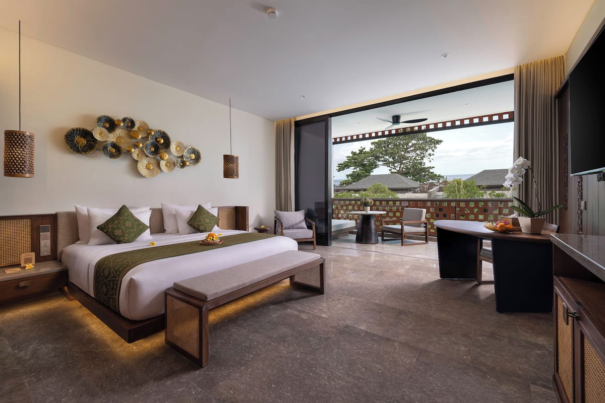 Quarto de hotel moderno com uma cama grande, uma escrivaninha e uma varanda com vista.