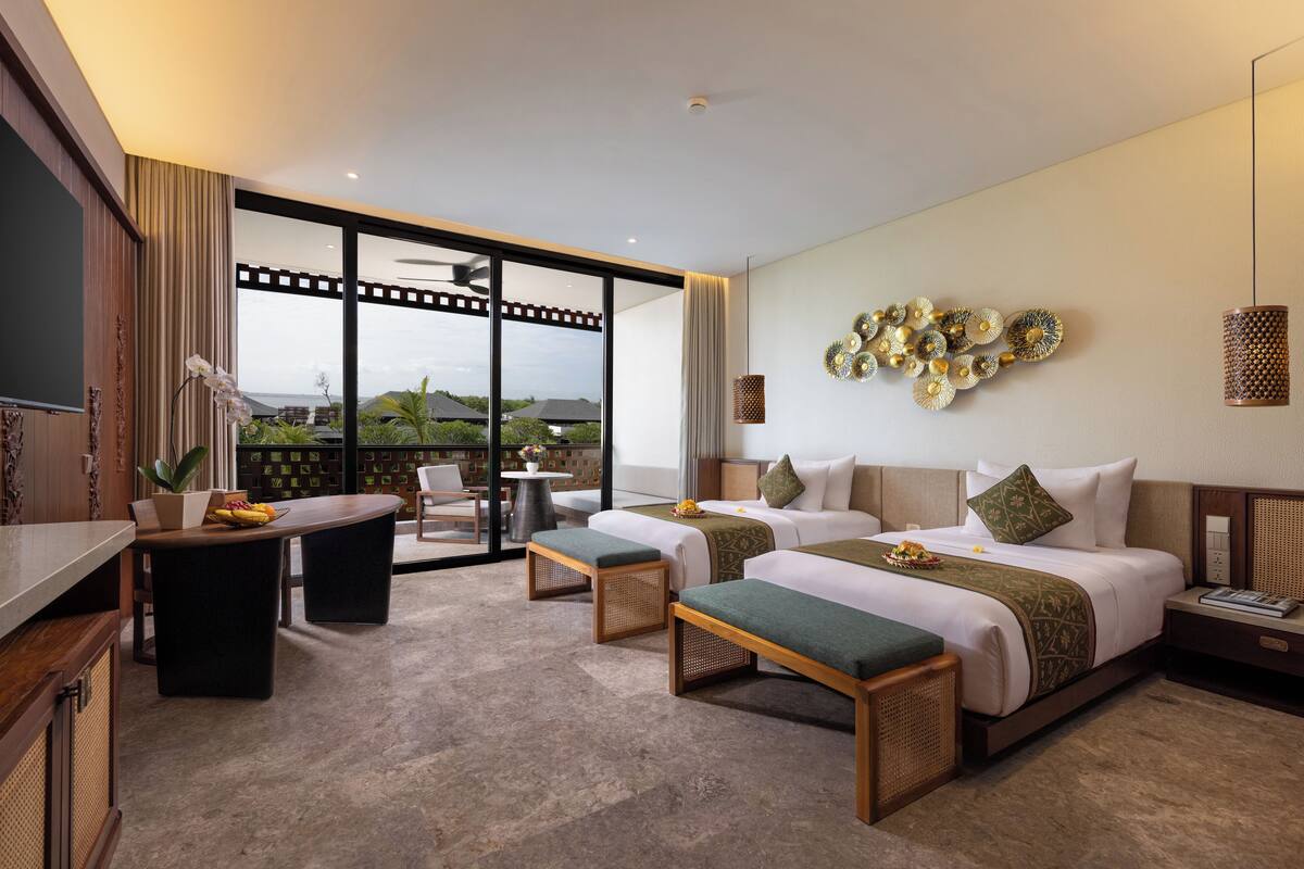 Quarto de hotel com duas camas, área de refeições e varanda com vista.