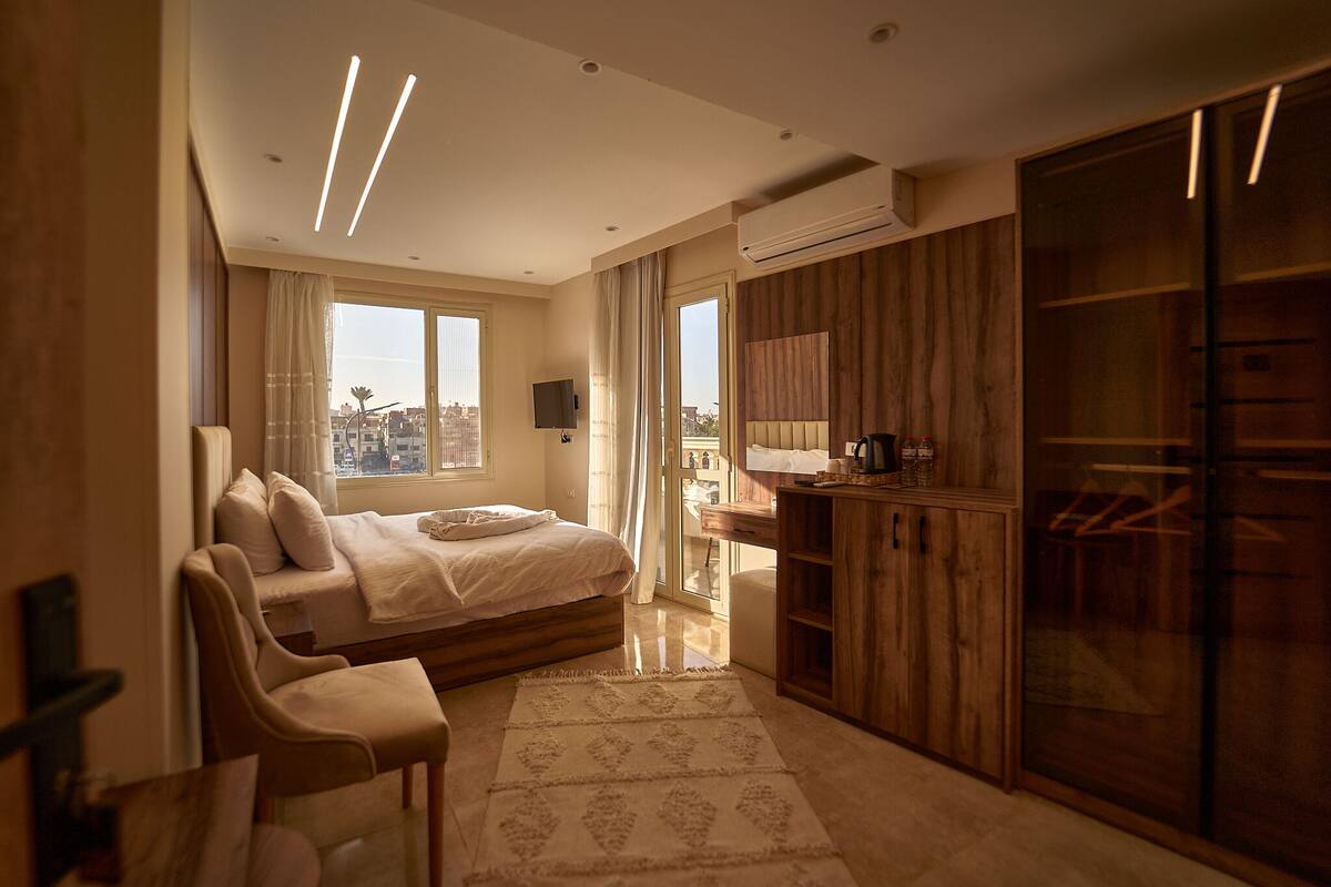 Quarto de hotel moderno com uma cama grande, uma escrivaninha, um guarda-roupa e vista para a cidade.