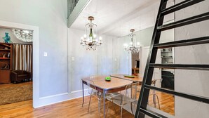 Uma sala de jantar com mesa e cadeiras de madeira, um candelabro e um espelho refletindo o ambiente.
