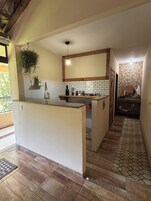 Uma cozinha compacta com ilha central, planta pendente e painel de azulejos.