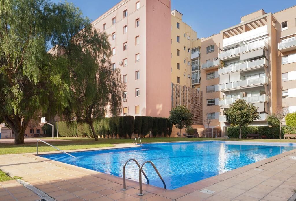 Piscina rodeada por edifícios de apartamentos, com céu claro acima.